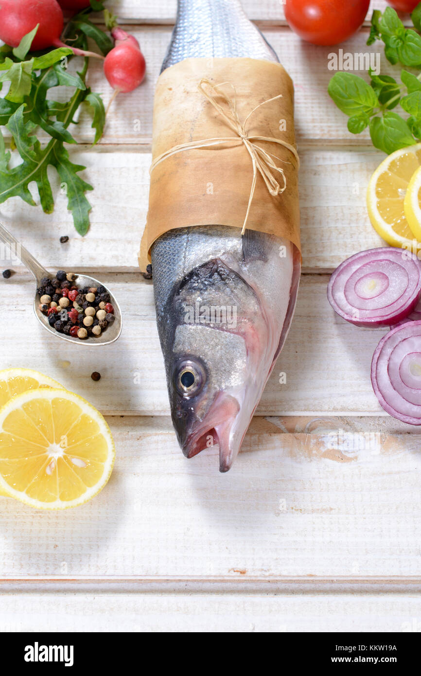 Raw bass fish with vegetables on the wooden background,selective focus ...