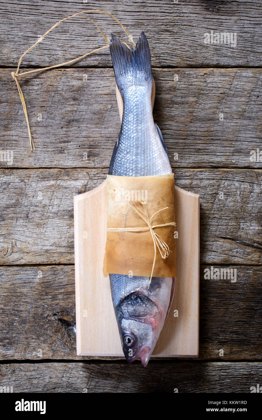 Single raw bass fish from above on the wooden background,selective ...