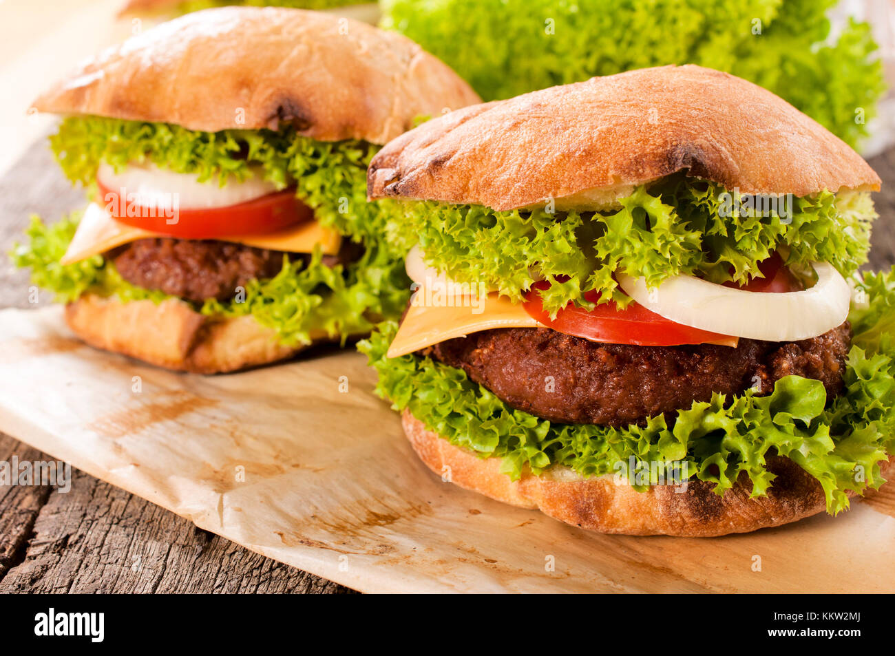 Selective focus on the right beef cheeseburger with vegetables and ...