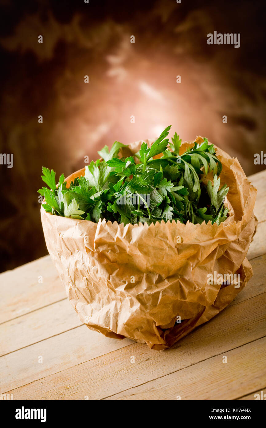 photo of fresh parsley inside a paper bag on wooden table Stock Photo ...