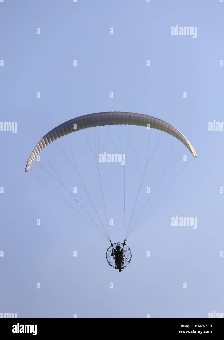 motorized paraglider with large propeller behind flies high in the sky ...