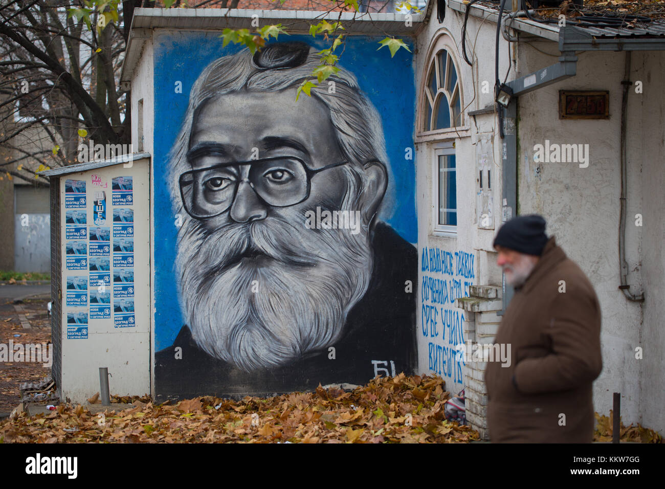 Bearded man walking along portrait graffiti of Radovan Karadzic alias ...