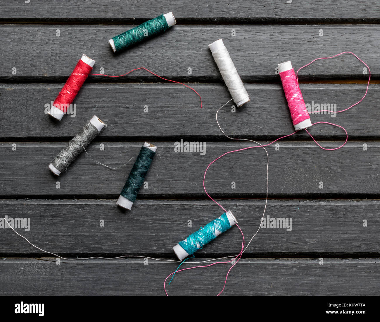 Colorful and colored sewing threads spread over a dark wooden ...