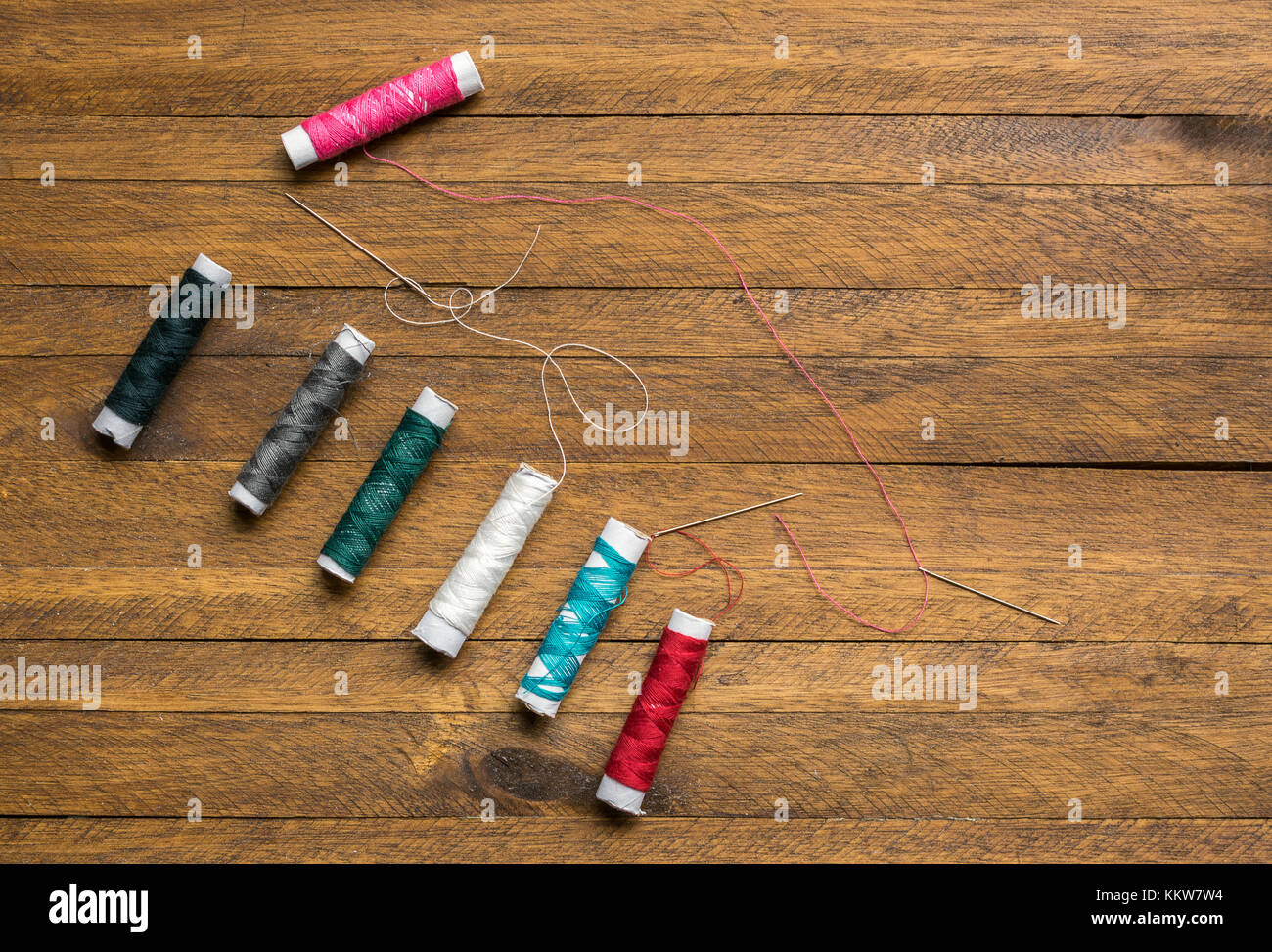 Colorful and colored sewing threads spread over a dark wooden ...
