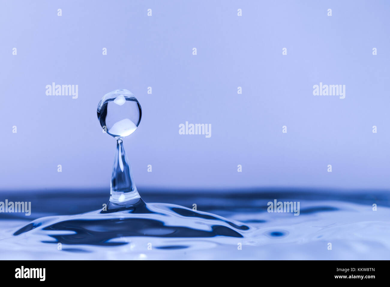 Close up of water drop dropping into water Stock Photo - Alamy