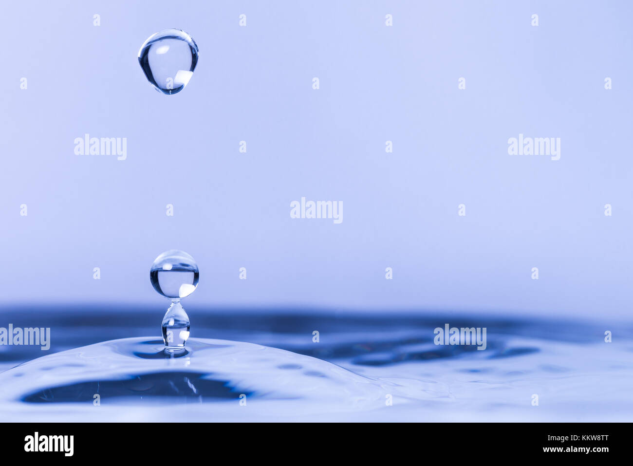 Close up of water drop dropping into water Stock Photo - Alamy