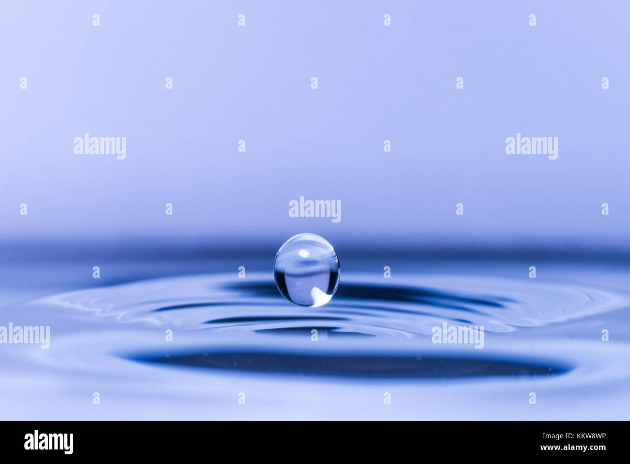 Close up of water drop dropping into water Stock Photo - Alamy