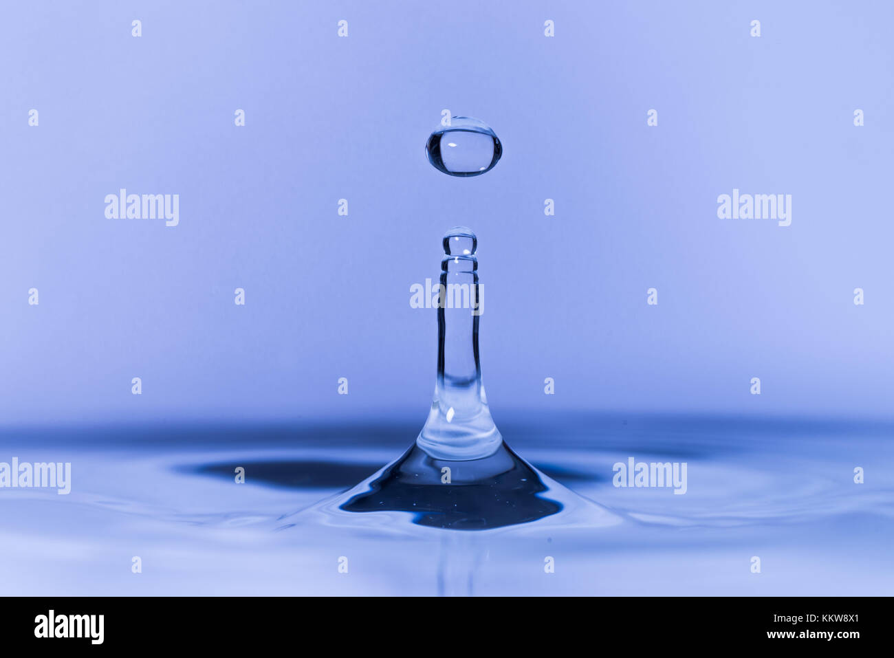 Close up of water drop dropping into water Stock Photo - Alamy
