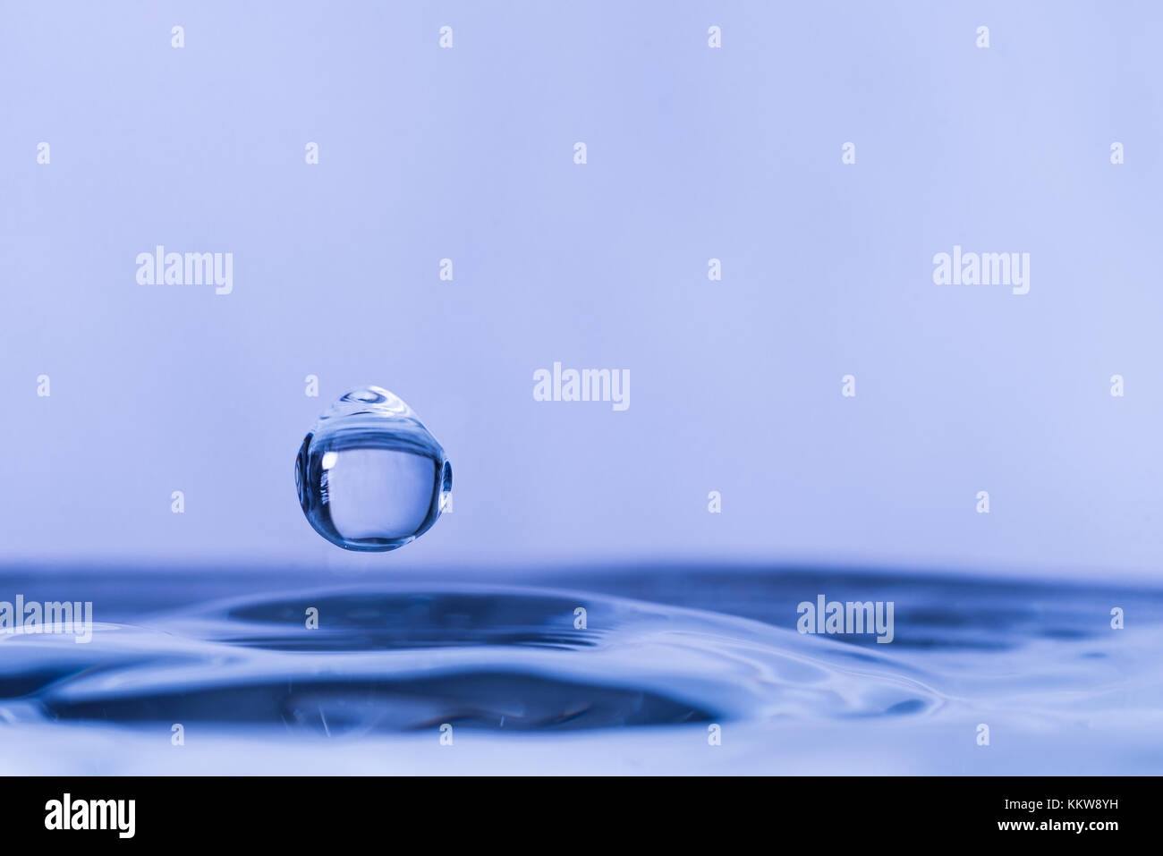 Close up of water drop dropping into water Stock Photo - Alamy
