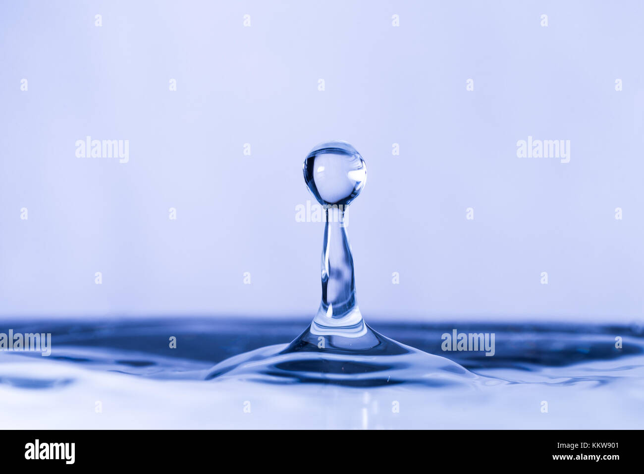 Close up of water drop dropping into water Stock Photo - Alamy