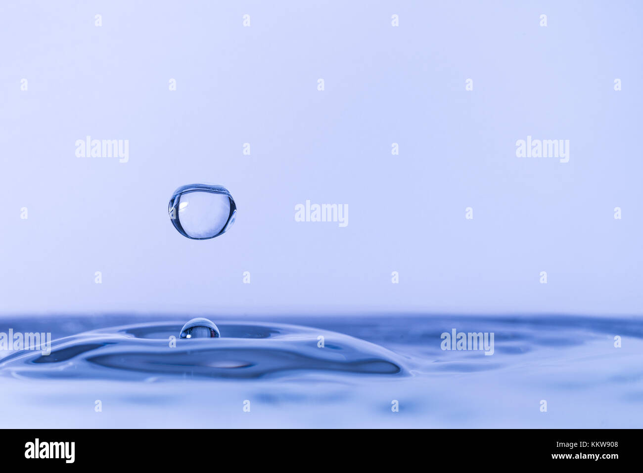Close up of water drop dropping into water Stock Photo - Alamy