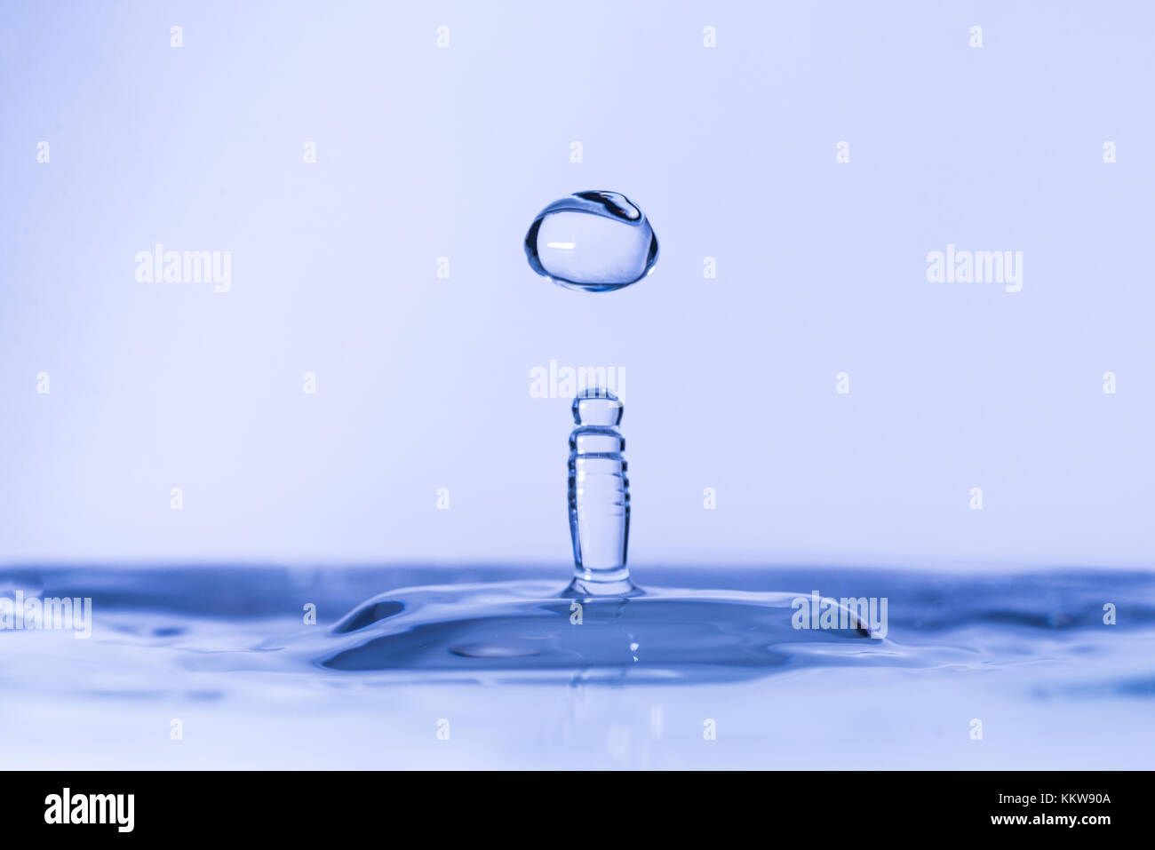 Close up of water drop dropping into water Stock Photo - Alamy