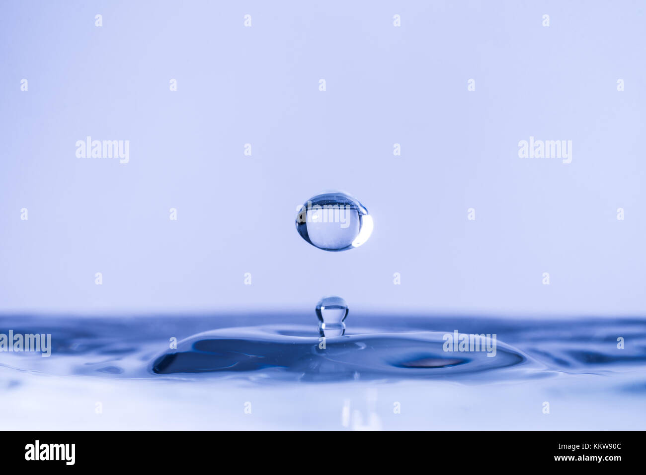 Close up of water drop dropping into water Stock Photo - Alamy