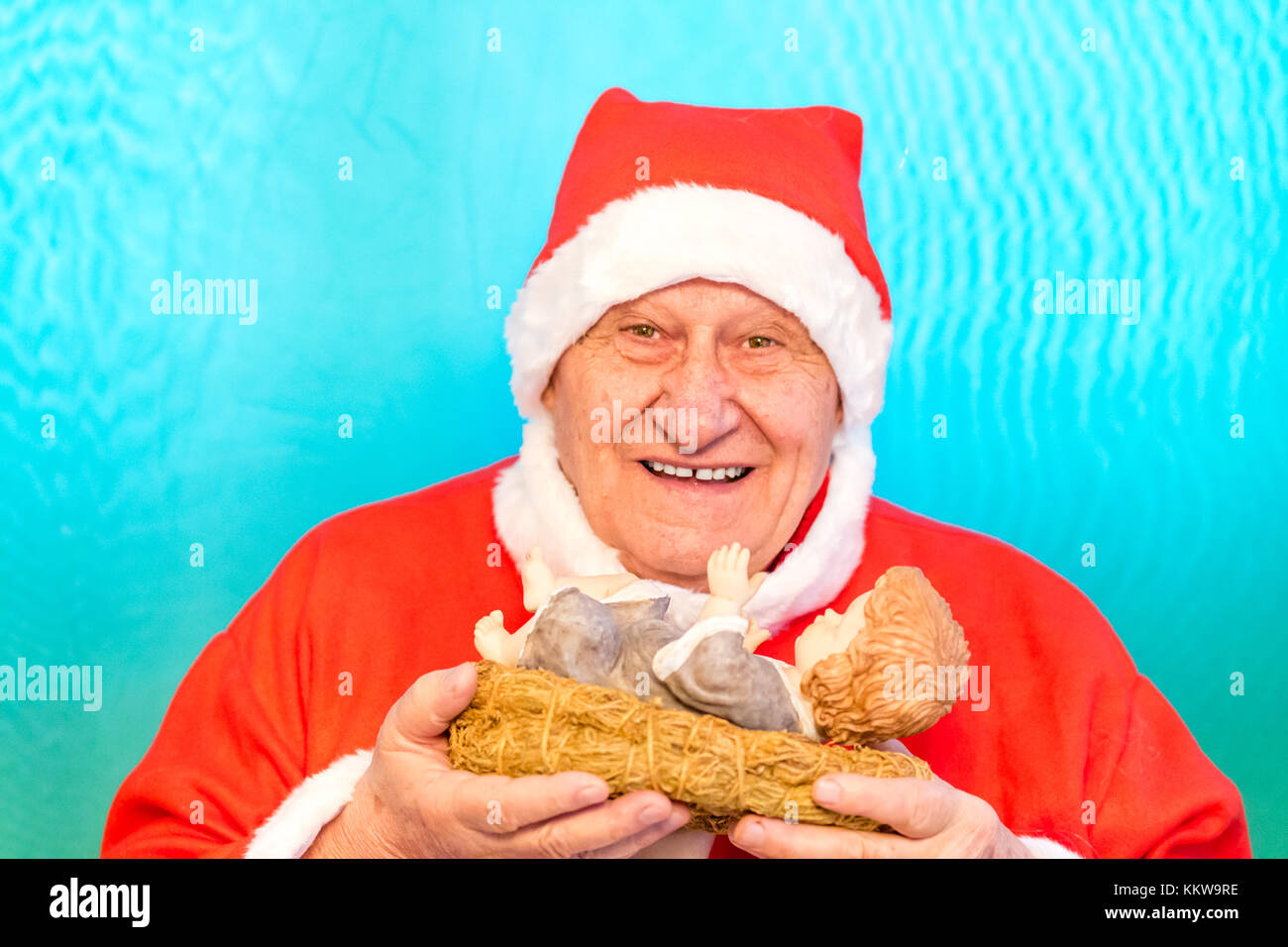 old man wearing Santa Claus costume smiling while holding a statue of ...