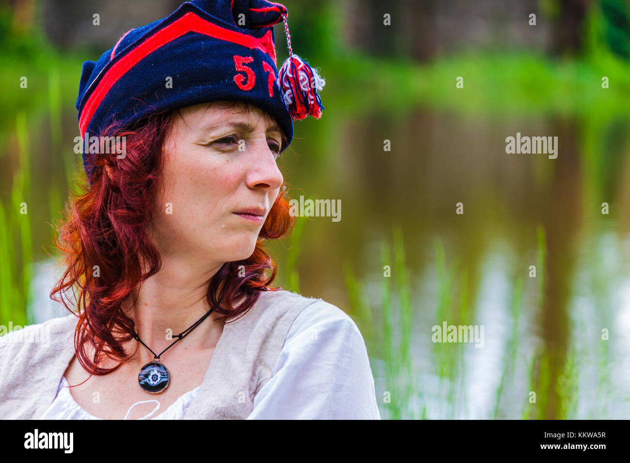 Woman of the napoleonic period sitting on the grass with worried facial ...