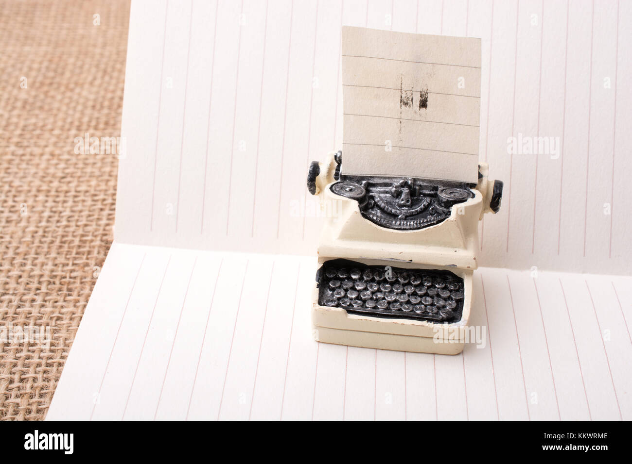 Retro syled tiny typewriter model on a paper background Stock Photo - Alamy