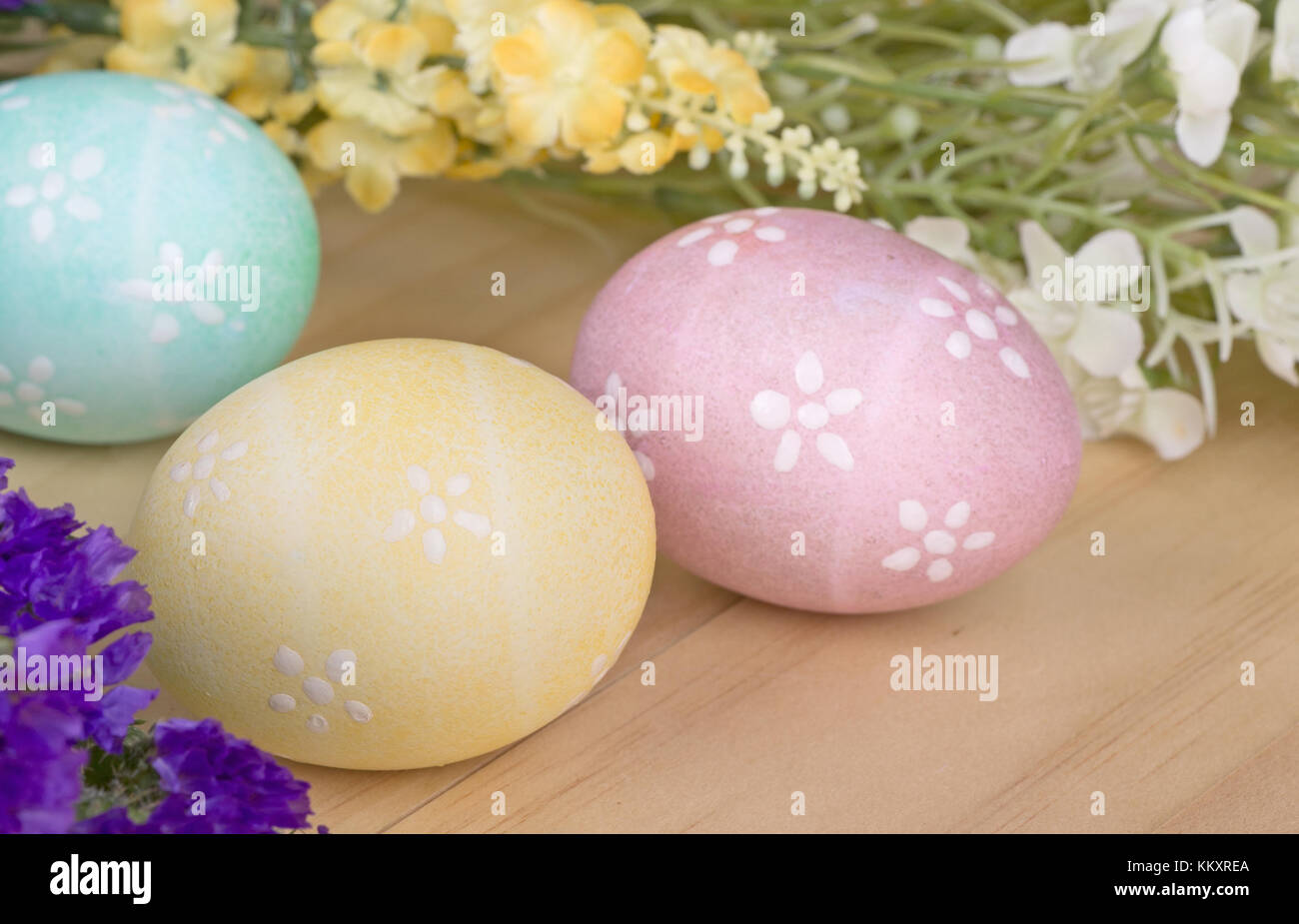 Three colored Easter eggs and flowers on a wood surface Stock Photo - Alamy