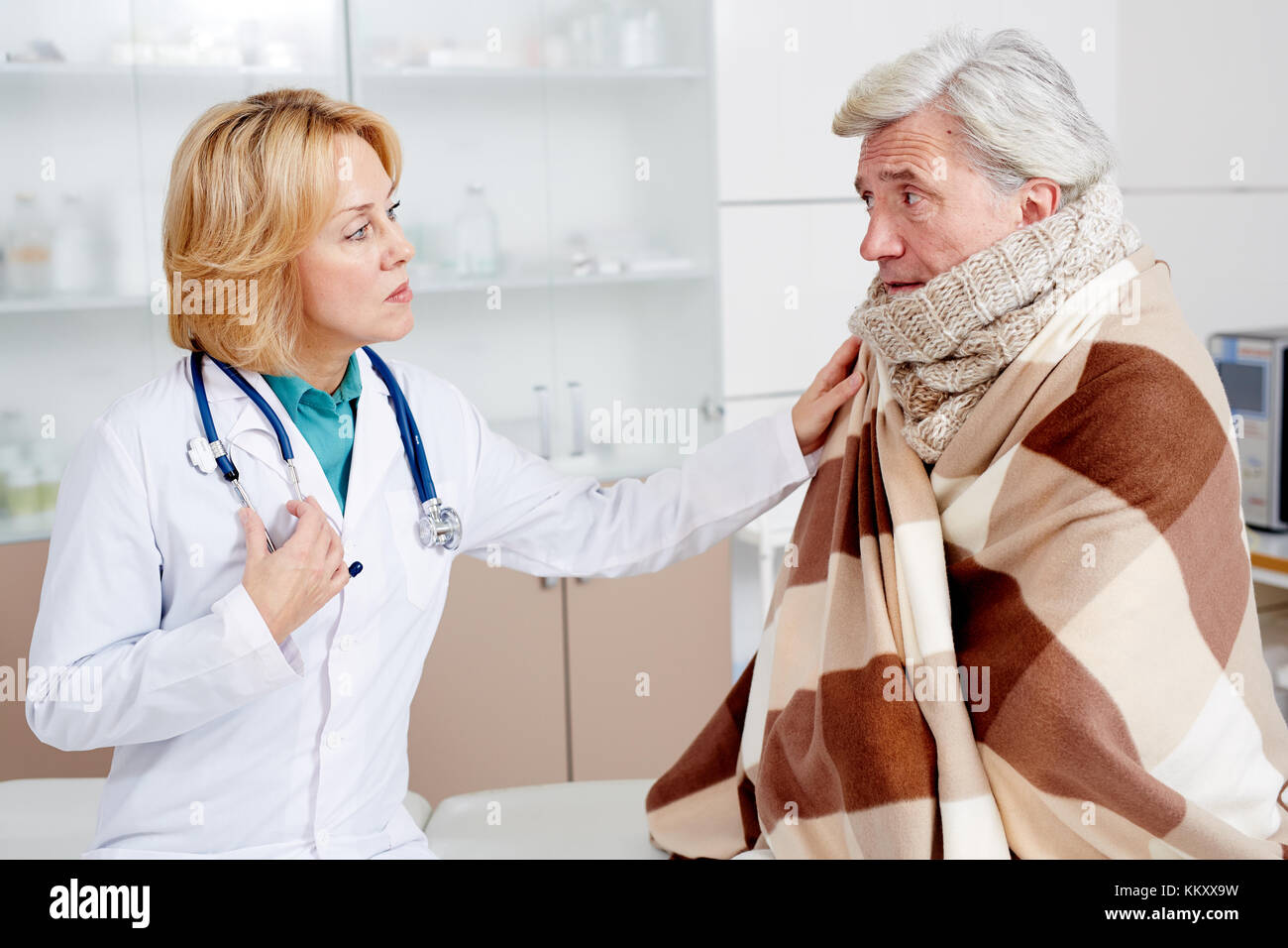 Mid-aged therapeutist supporting her sick patient wrapped into plaid ...