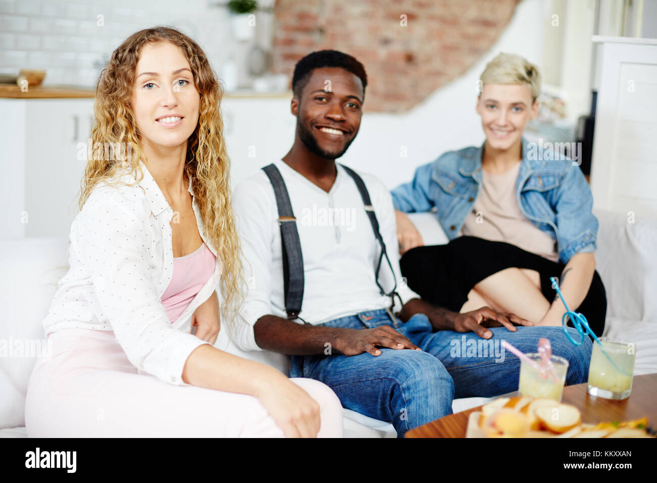Young intercultural people relaxing at home in living-room after ...