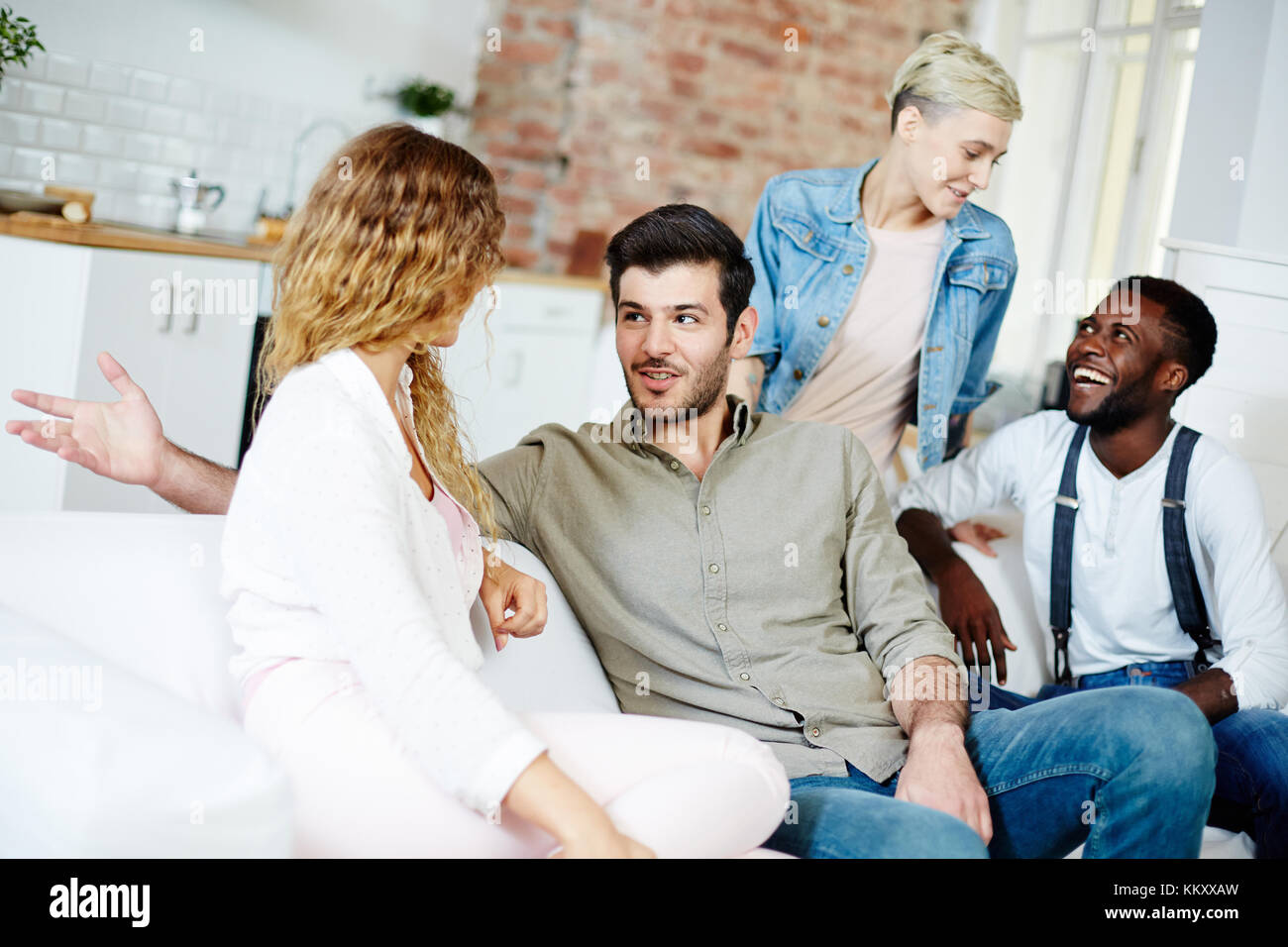 Two happy young couples talking during gathering at home on weekend ...