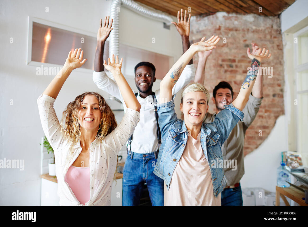 Group of young companions raising their hands while dancing at leisure ...