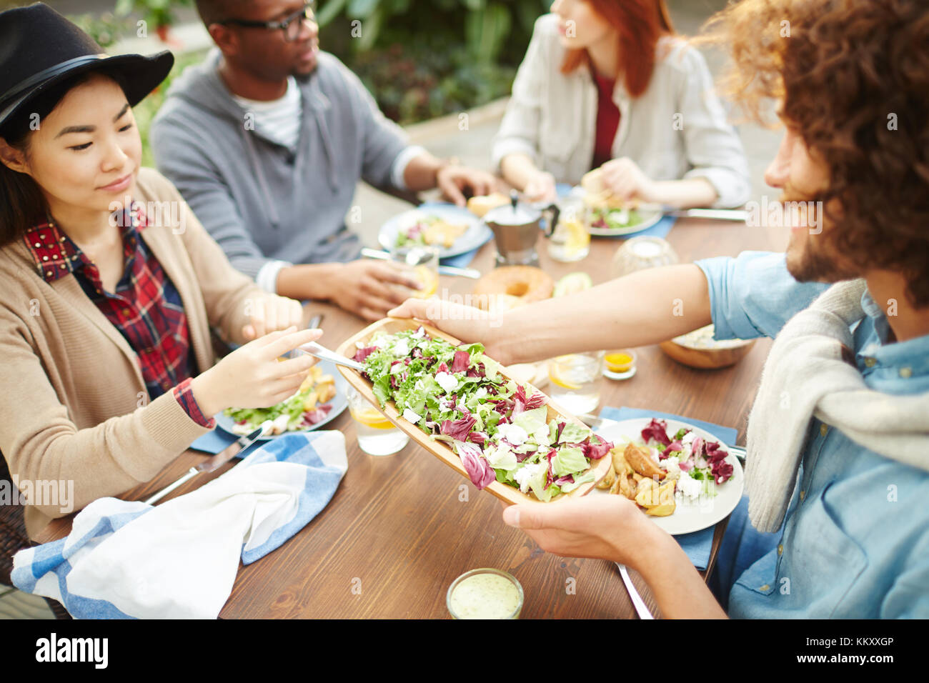 Friendly guy offering fresh homemade vegetable salad to one of girls by ...