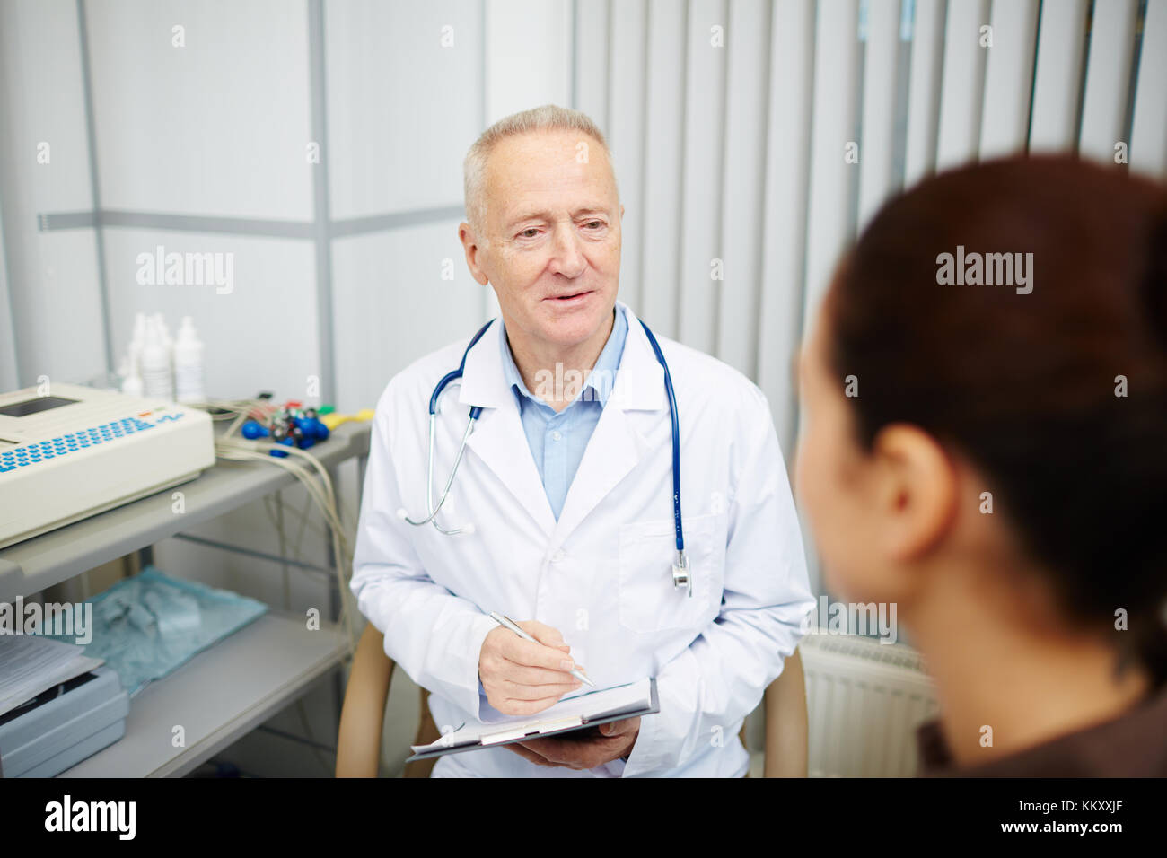 Confident therapeutist talking to young patient during appointment in ...