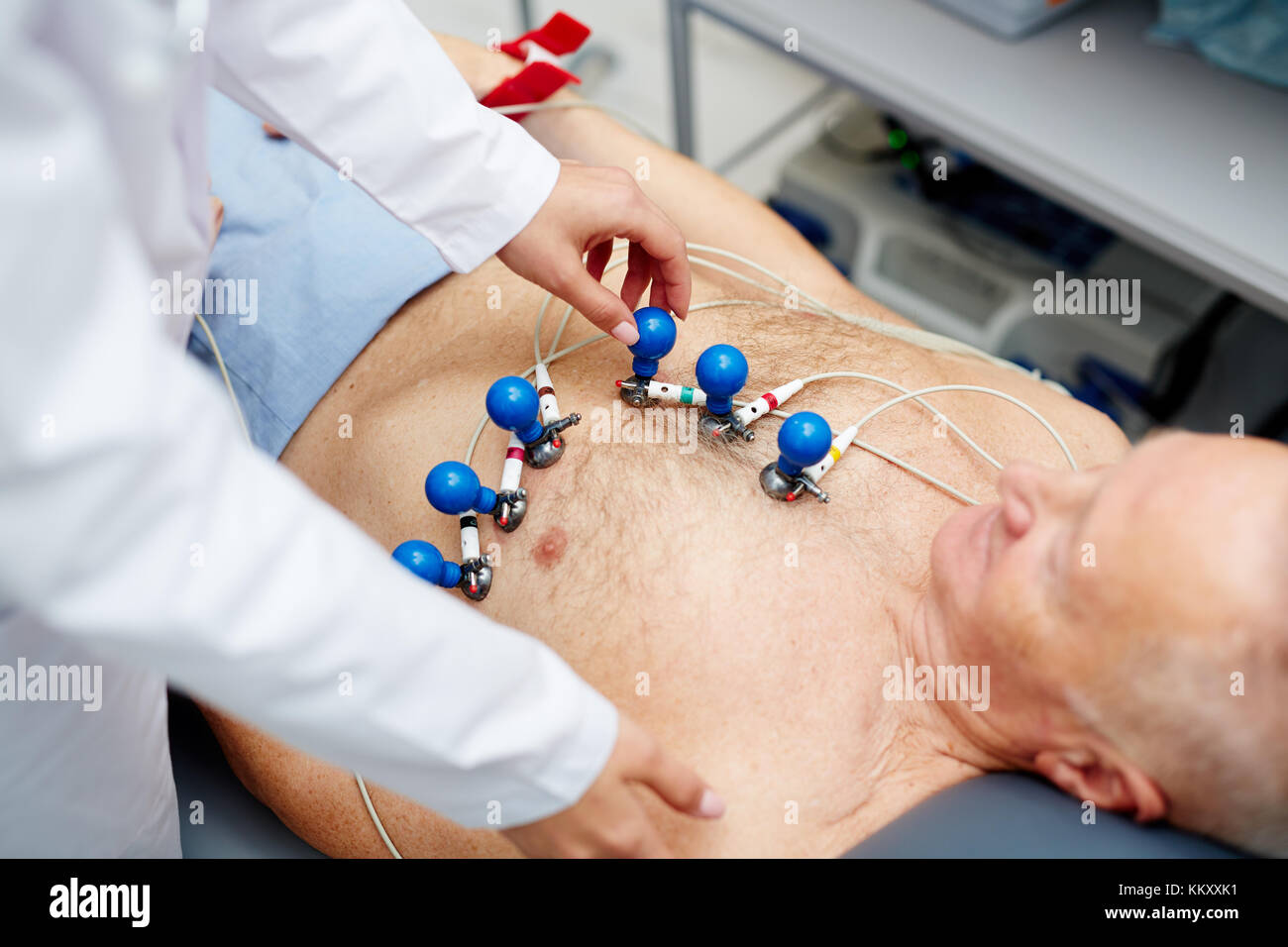 Cardiologist putting special equipment on chest of patient before ...