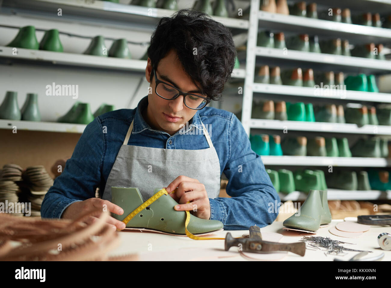 Professional cobbler taking measures from unfinished boot by his ...