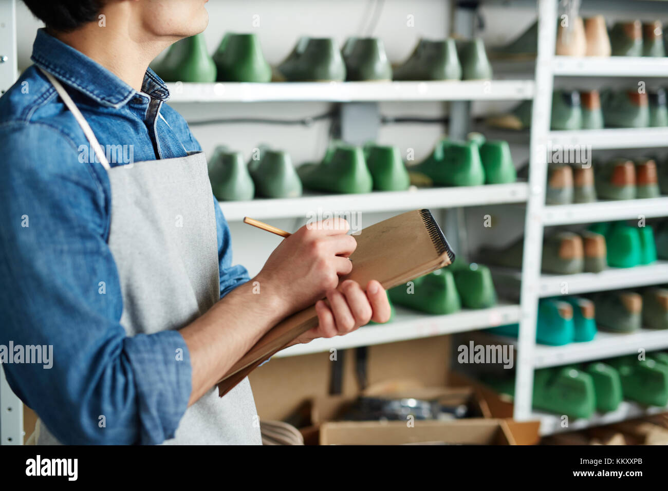 Shoemaker with notepad and pencil making revision of workpieces in his ...