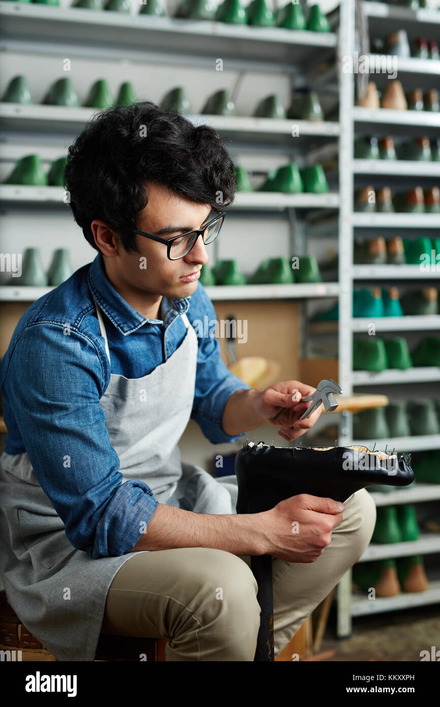 Cobbler with handtool taking out nails from shoe sole while repairing ...