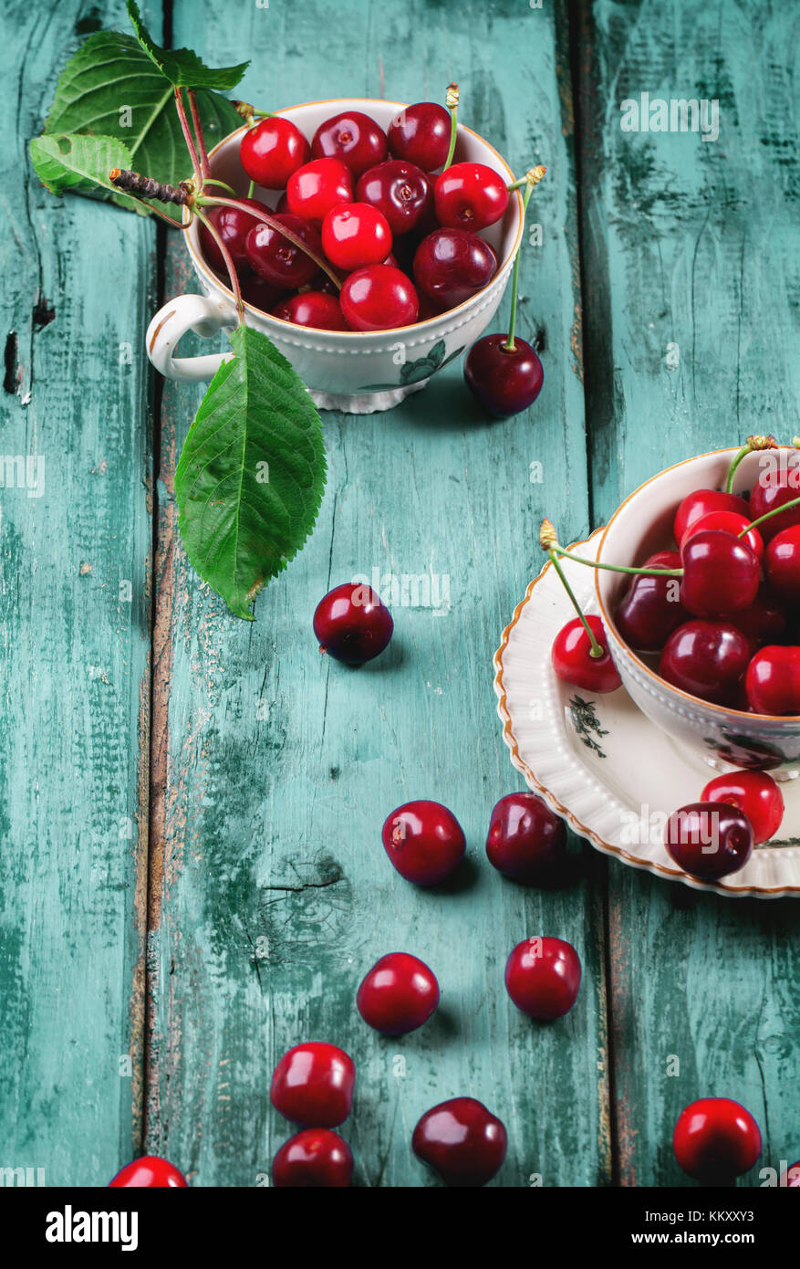 Fresh cherries in vintage tea cups on blue wooden table Stock Photo - Alamy