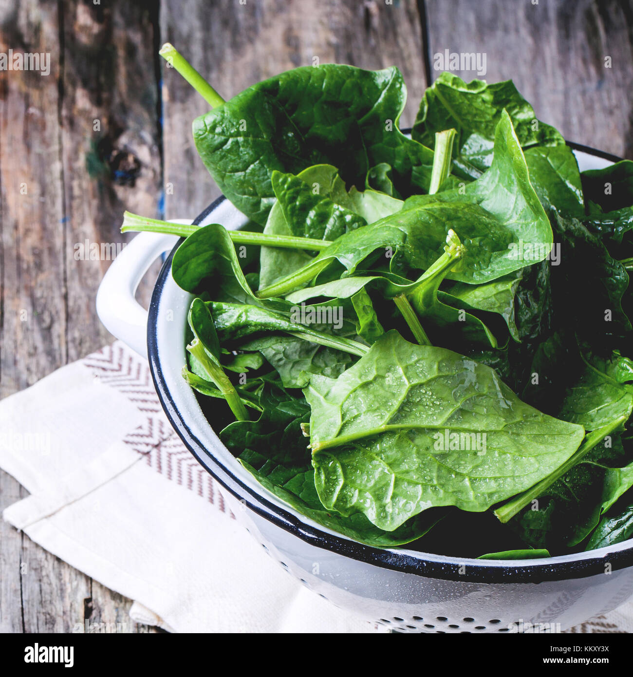 Fresh spinach in metal colander over wooden background. Square image ...