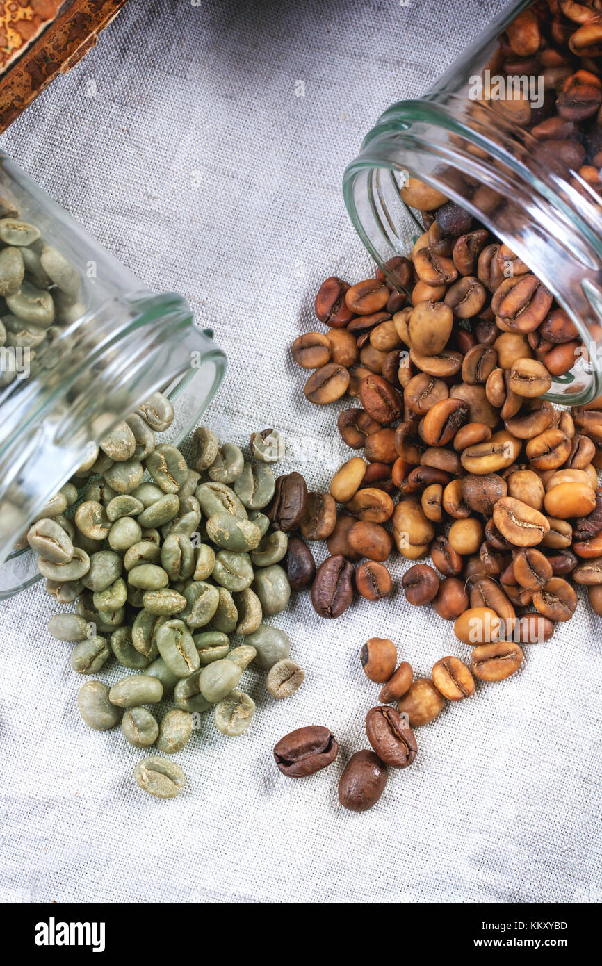 Glass jars with green and brown decaf unroasted coffee beans on ...