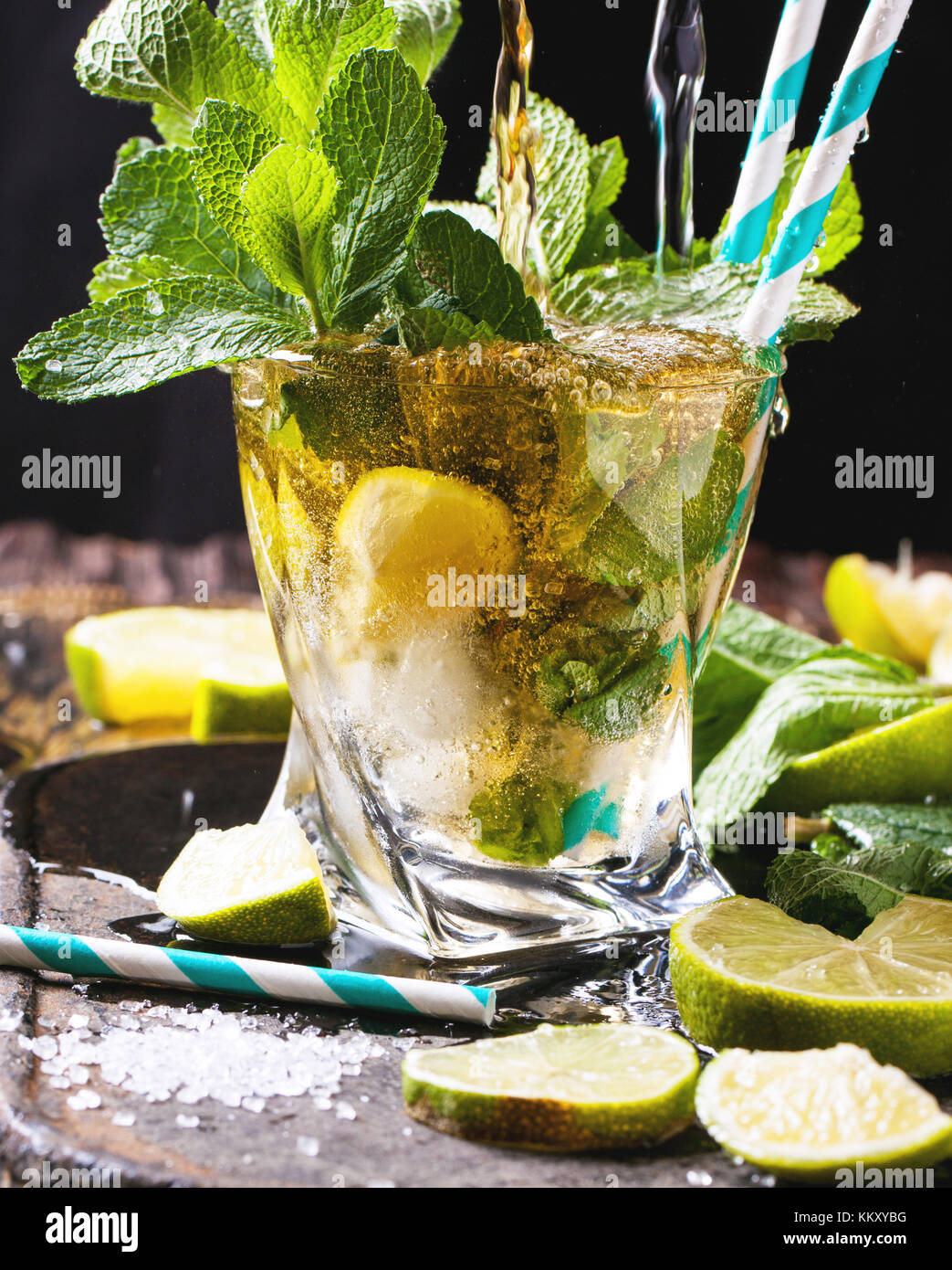 Glass of mojito cocktail with pouring rum and soda, fresh mint, limes ...