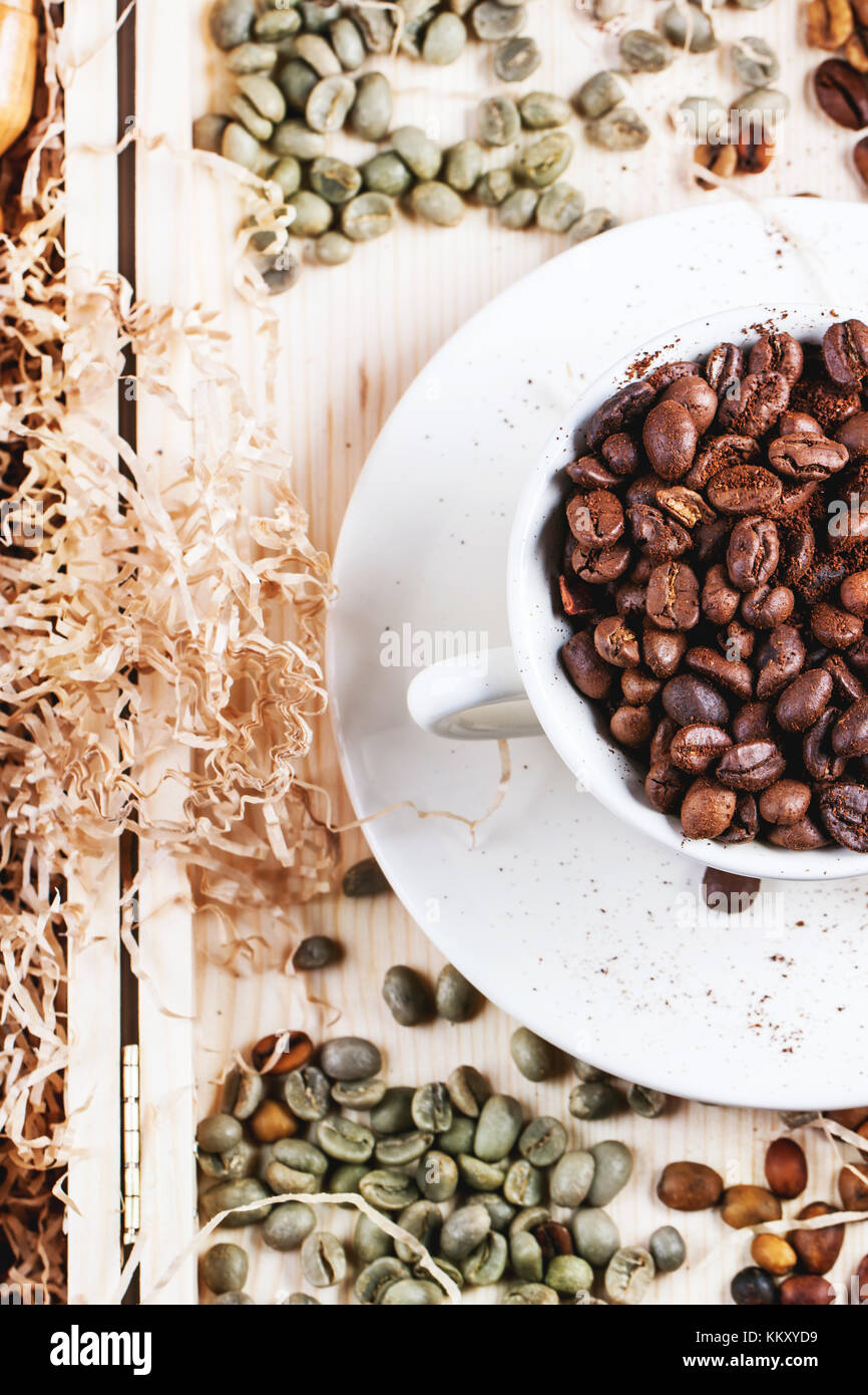 Green and brown decaf unroasted coffee beans and cup of roasted coffee ...