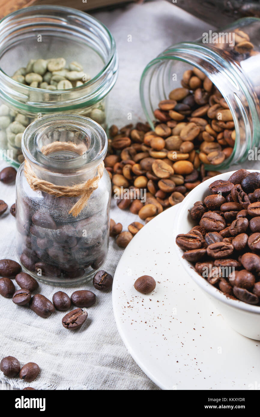 Green, brown unroasted decaf and black coffee beans in glass jars and ...