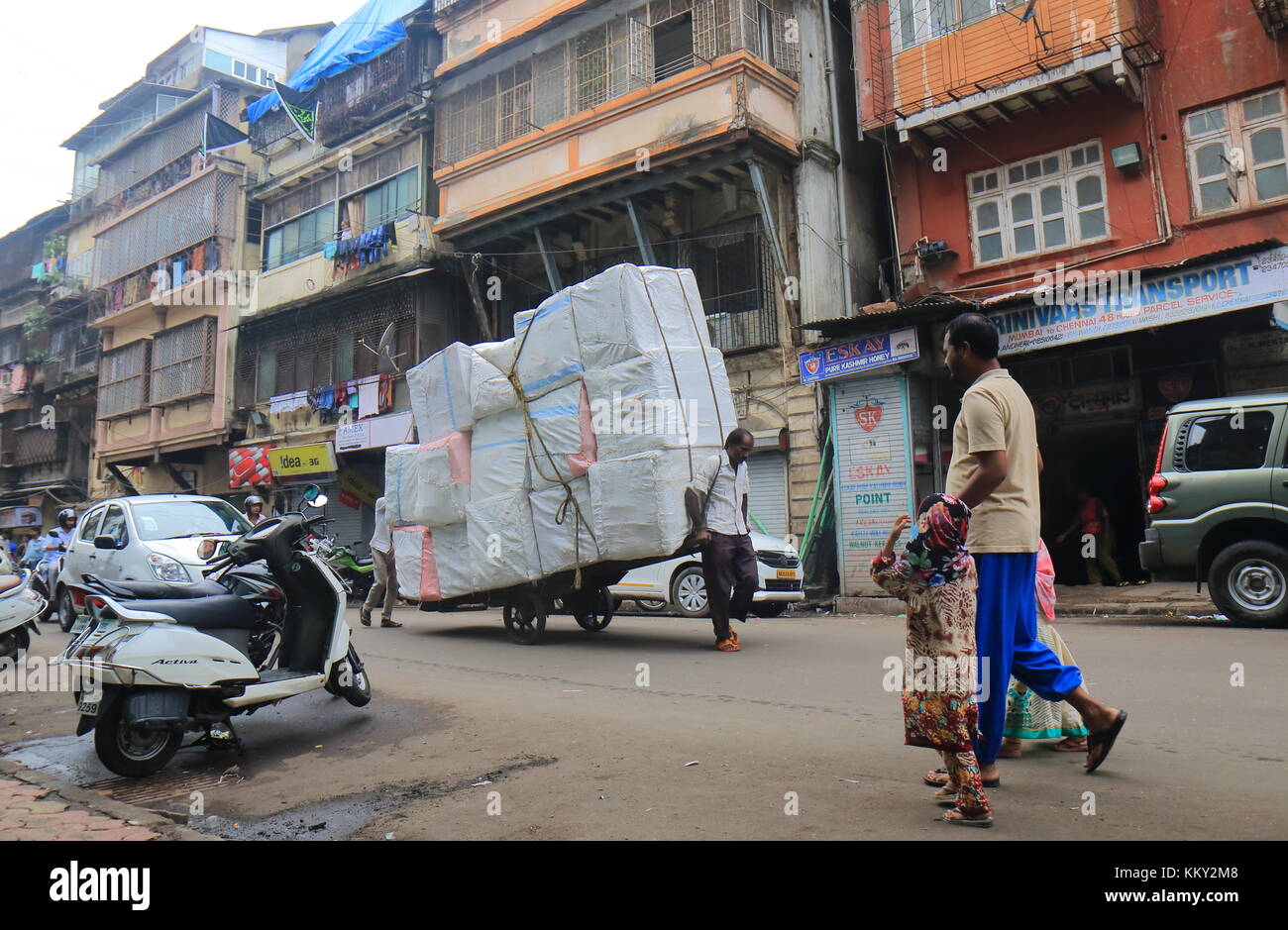 Unidentified man carries heavy loaded cart in downtown Mumbai India ...