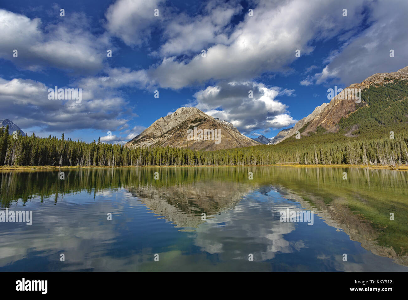 Big blue sky, mountains, and beautiful clouds reflect in still waters ...