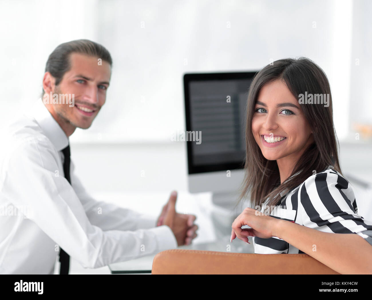 two young employee sitting behind a Desk Stock Photo - Alamy