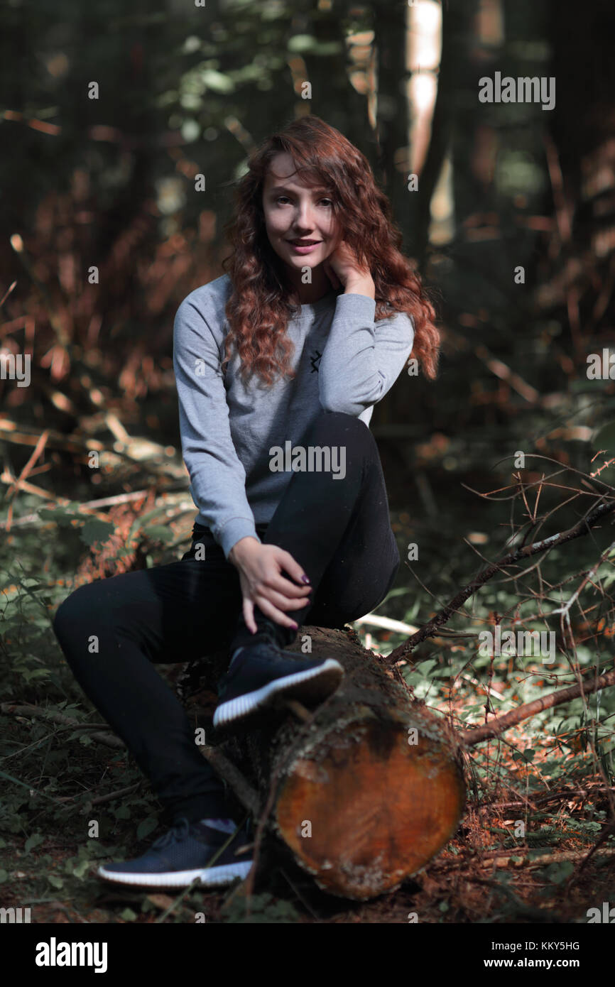 beautiful young woman sitting on a log Stock Photo - Alamy