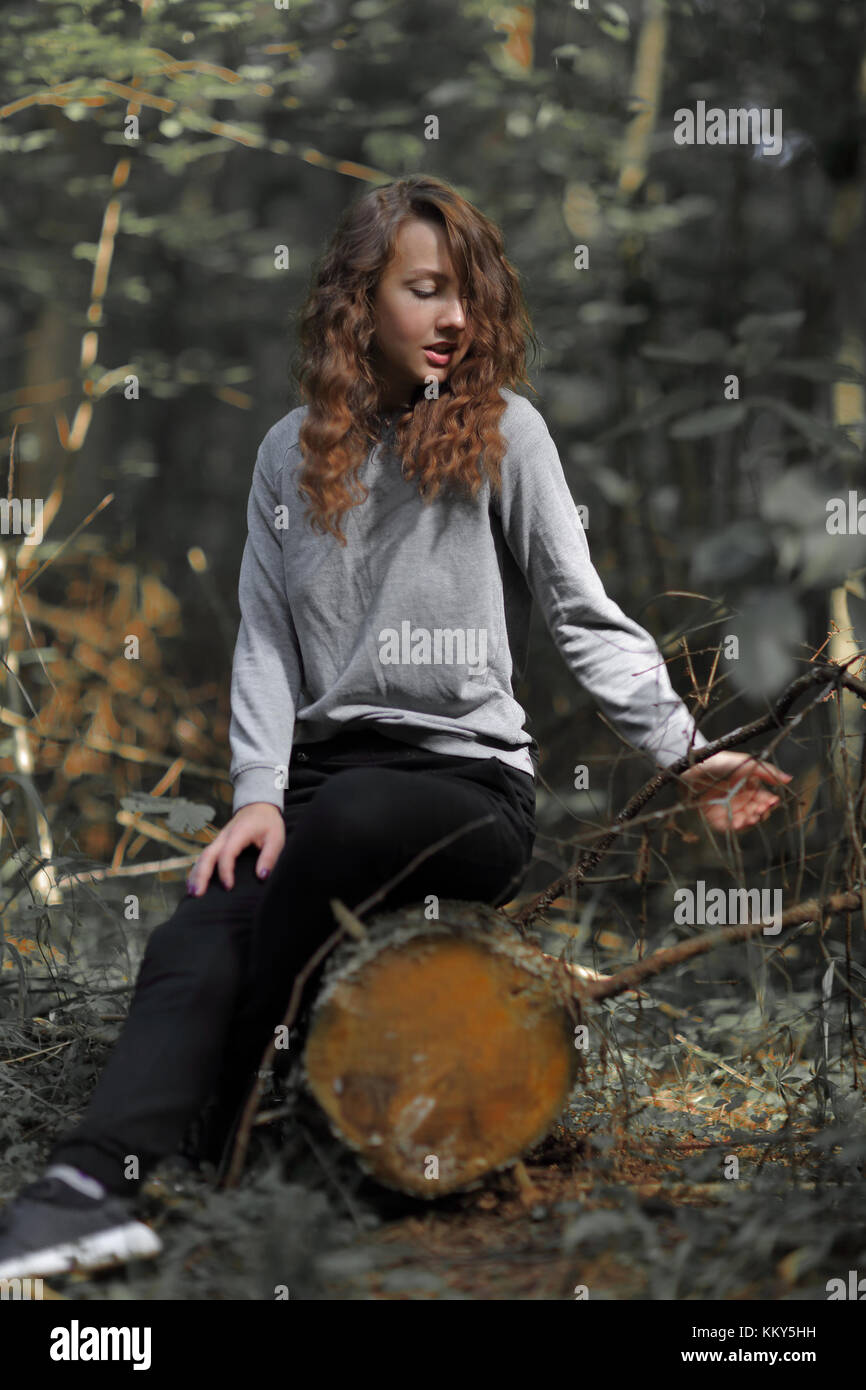 beautiful young woman sitting on a log Stock Photo - Alamy