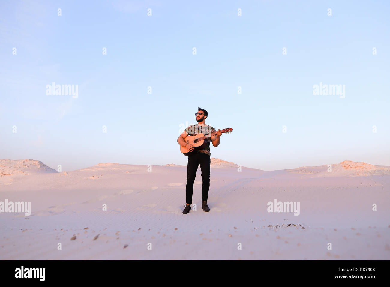 Young Muslim male performer and singer walks through sandy desert with ...