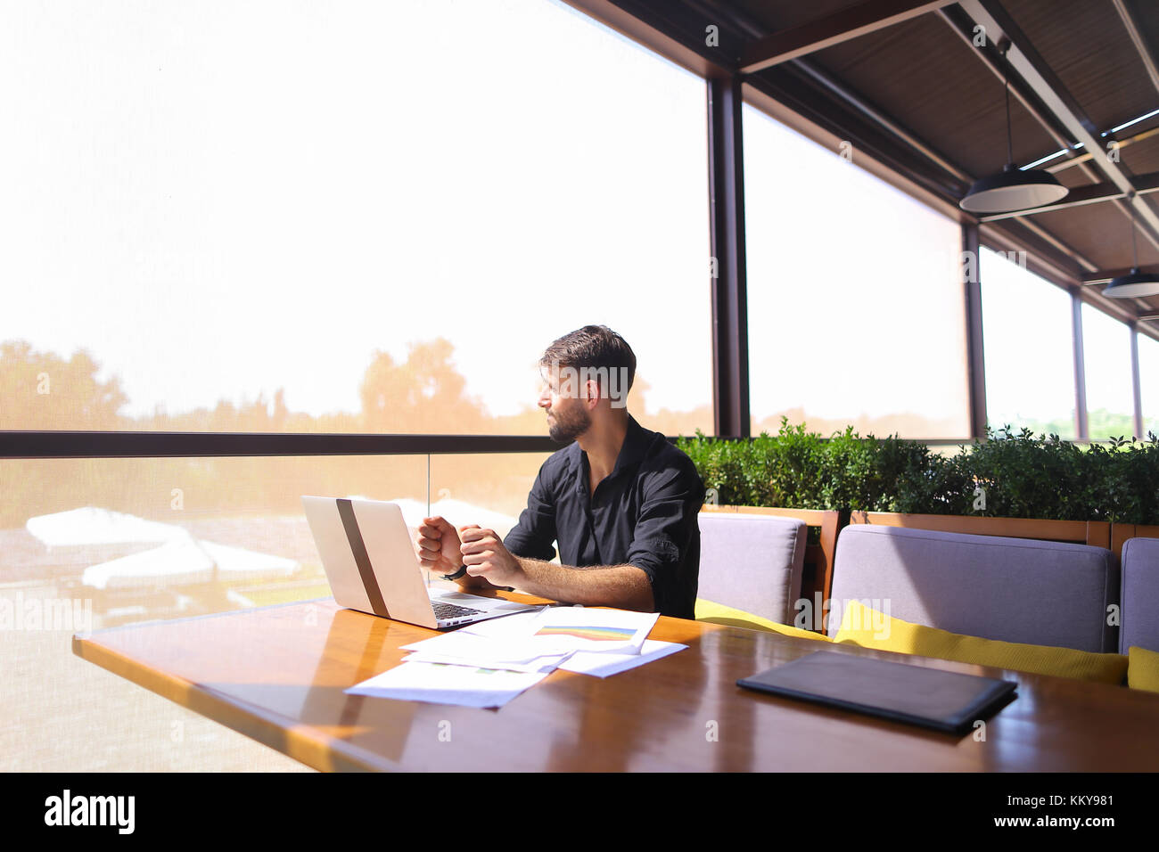 Tired quantity surveyor working at cafe table with diagram and ...
