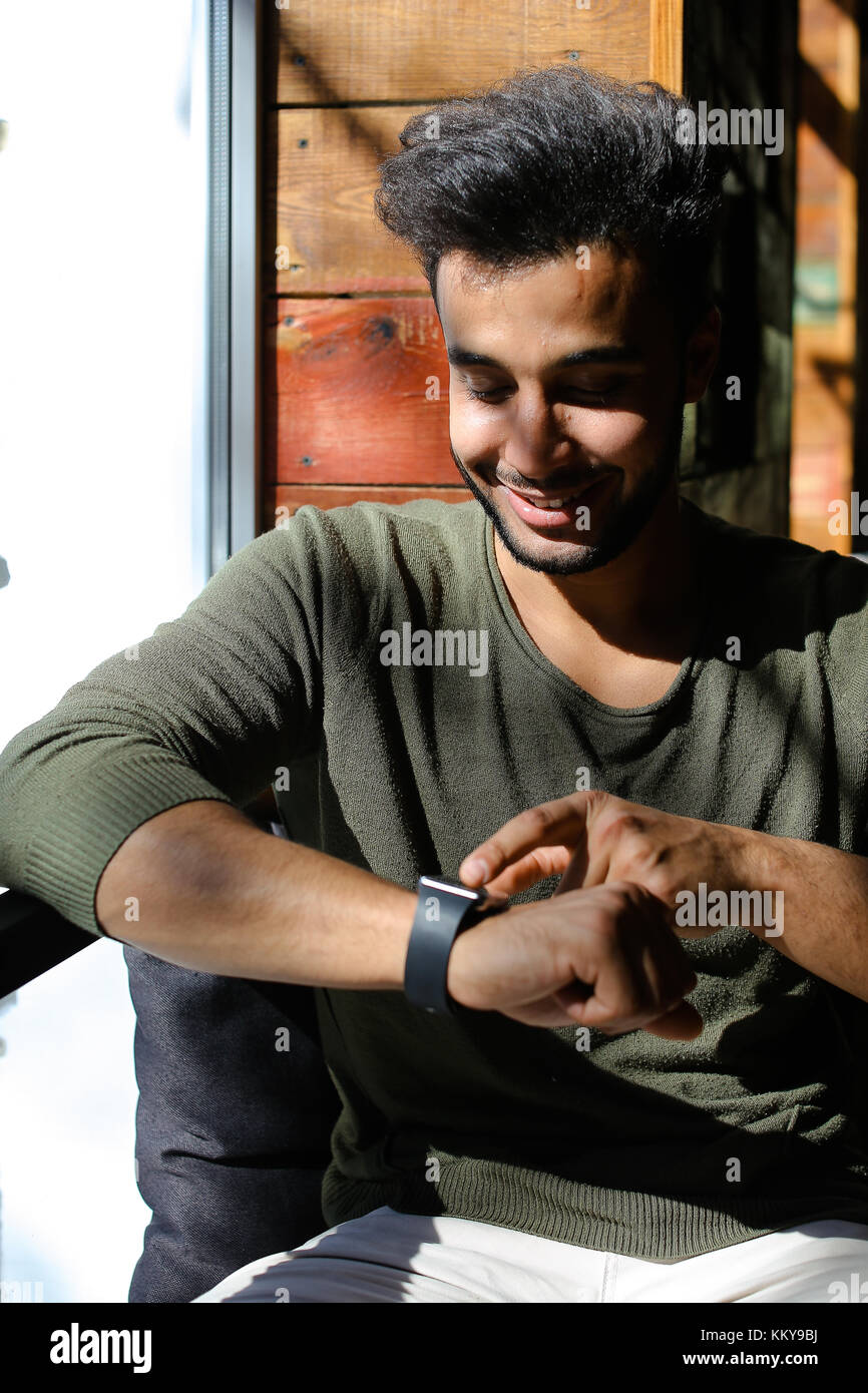 Arabian sits near window and uses smart watch in caf . Person dressed ...