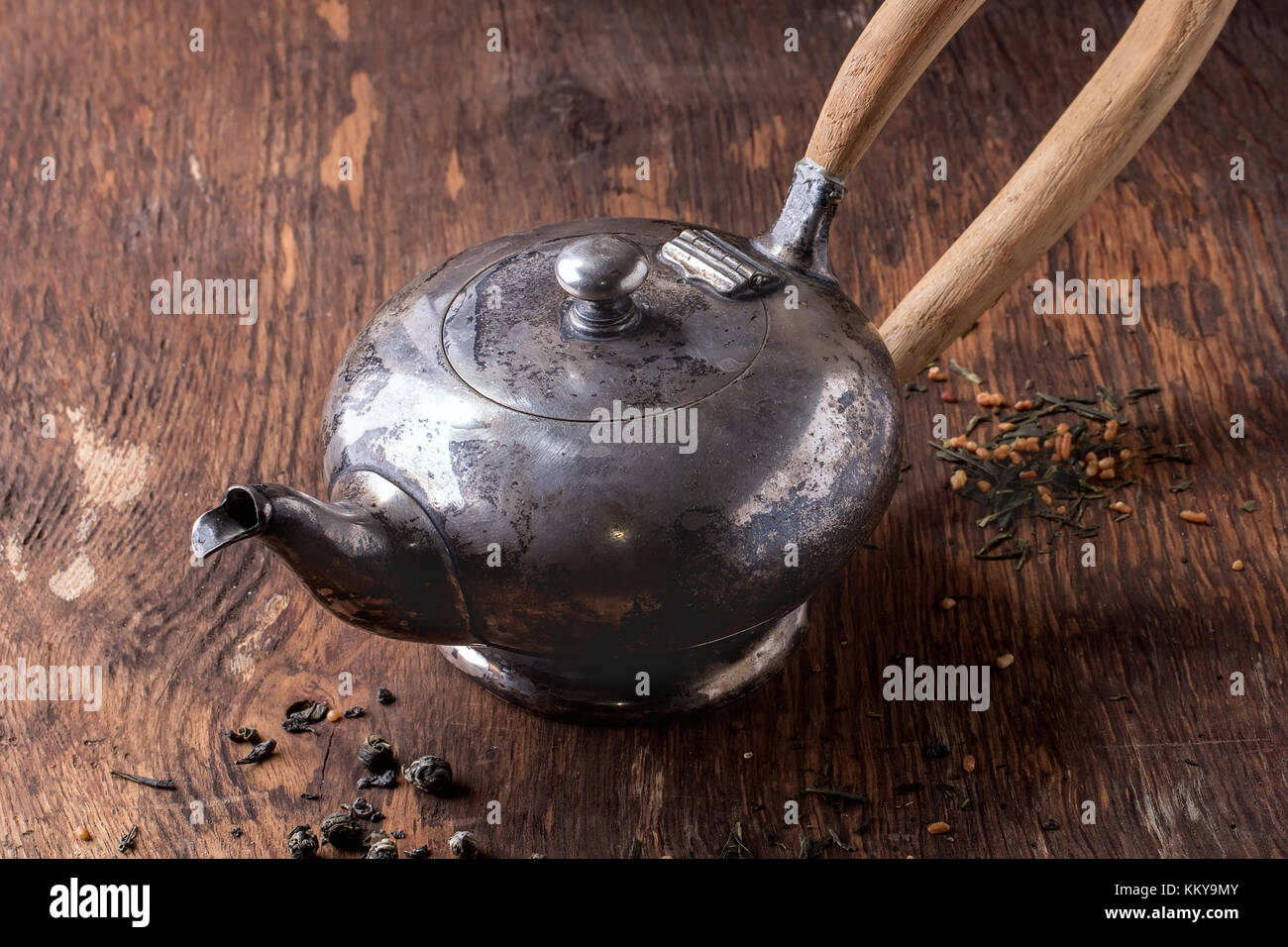 Vintage metal teapot with wooden handle. With dry green tea leaves on ...