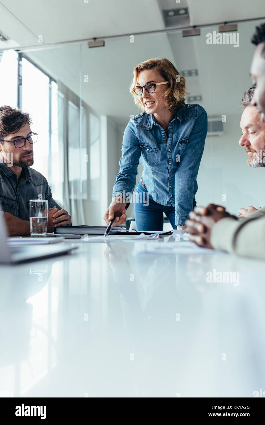 businesswoman explaining to coworkers about project in office ...