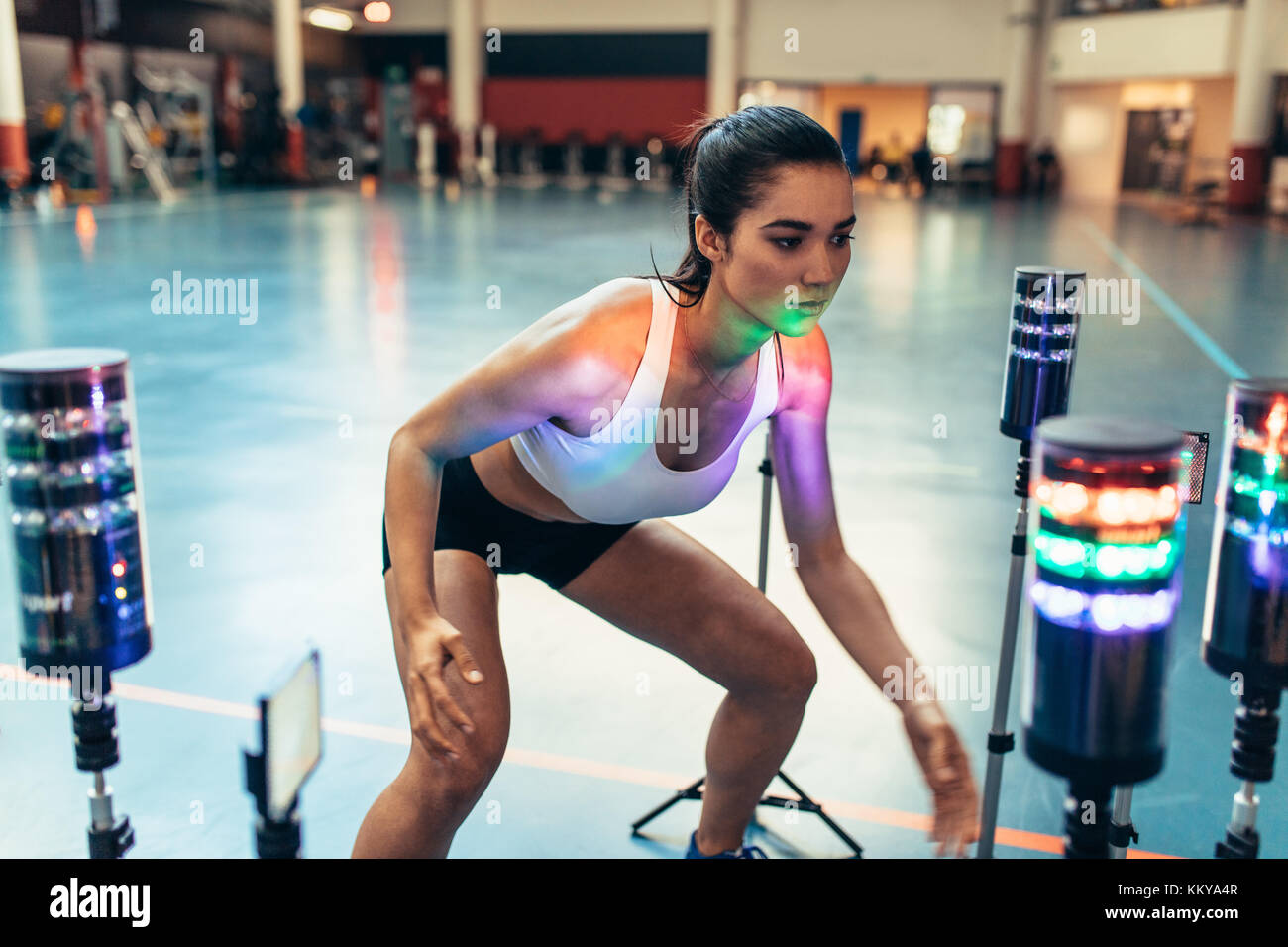 Fit young woman doing hand eye reaction training with lights sensors in ...