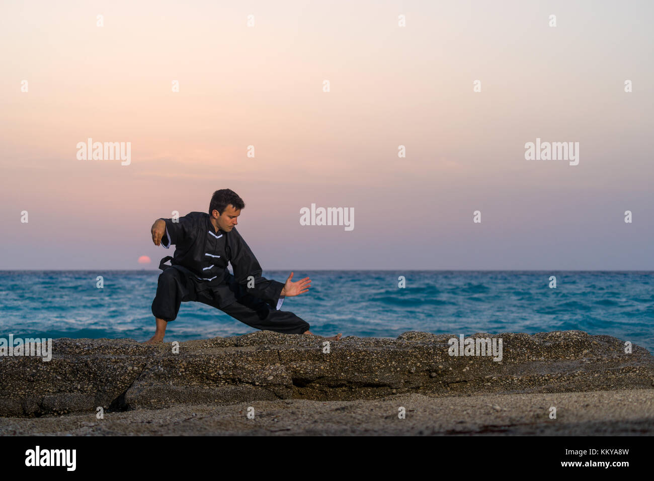 man performs tai chi moves agains sunset at the beach Stock Photo - Alamy