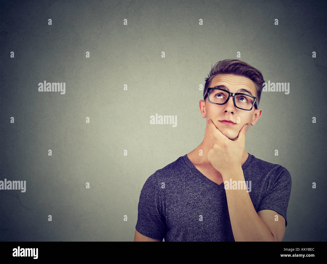 Handsome thoughtful young man wearing glasses making up his mind ...